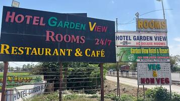 Placa do Hotel Garden View anunciando quartos, serviço 24 horas por dia e um restaurante e café.