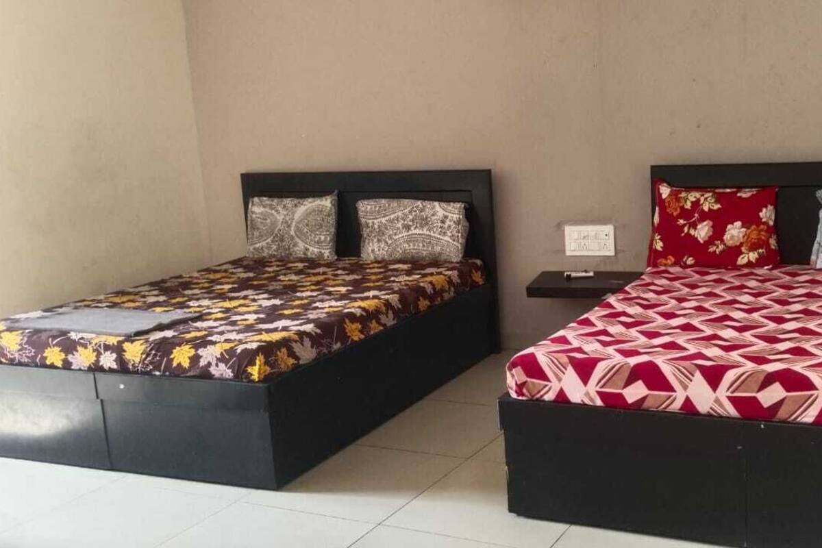 Duas camas com colchas estampadas e um criado-mudo com abajur no meio.