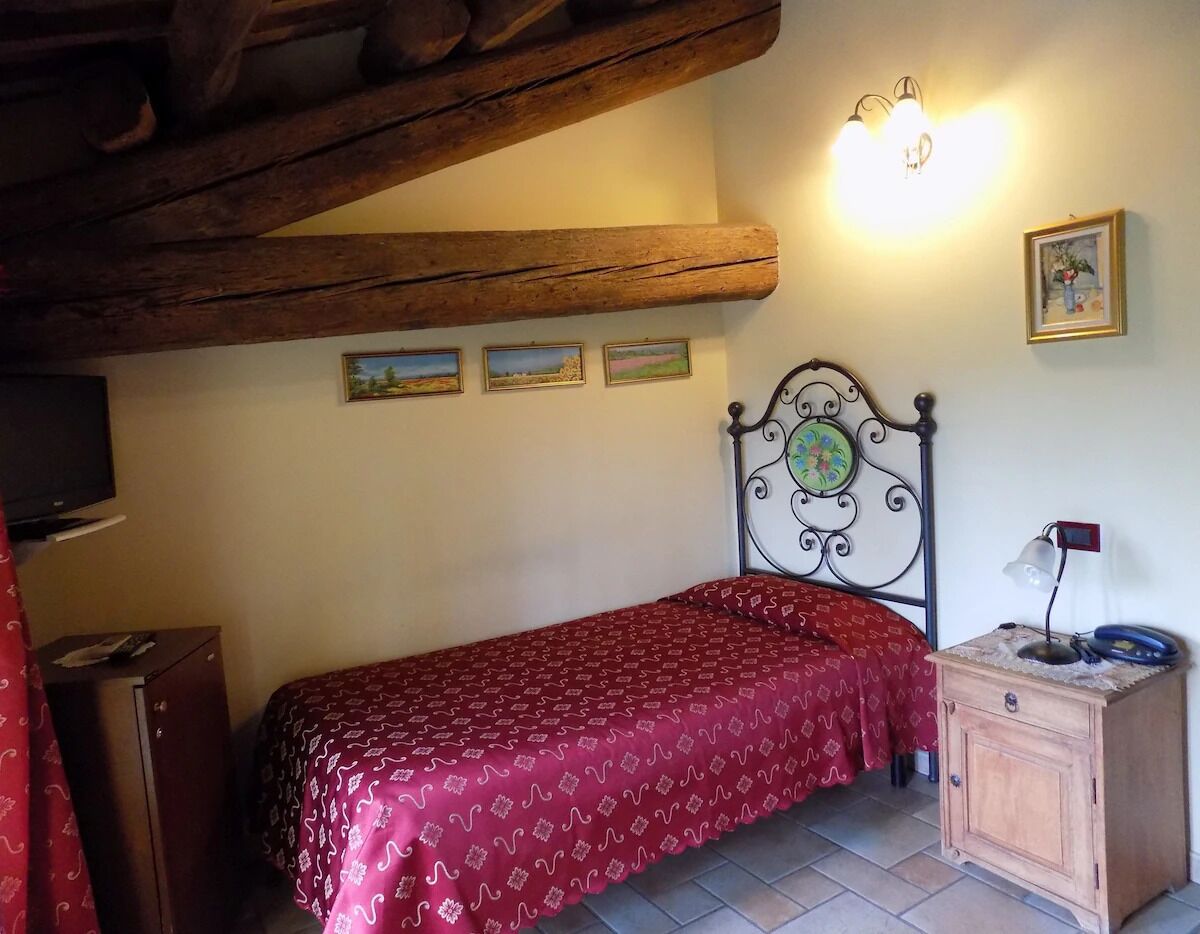 Um quarto com uma cama, um armário de madeira, uma luminária na parede e um quadro.