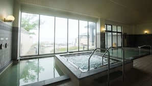 Uma área de spa com duas banheiras de hidromassagem, grandes janelas e piso revestido de azulejos.
