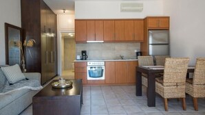 Uma cozinha compacta com armários de madeira, forno embutido e área de refeições com cadeiras de vime.
