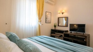Quarto com cama, televisão, escrivaninha e espelho.