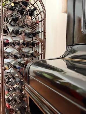 Uma estante para vinhos com várias garrafas, uma superfície de metal polido e uma visão parcial de um veículo.