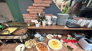 Disposição de buffet com diversos alimentos e utensílios.