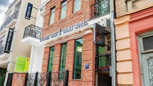 Um hotel com fachada de tijolos, uma varanda e uma placa com a inscrição 'DUMA HOTEL'.