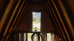 Um quarto com teto inclinado e janela com vista para a paisagem.