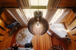 Interior em madeira com luminária de teto diferenciada, parede de mármore e uma banheira.