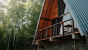 Uma casa moderna com telhado inclinado, janelas amplas e varanda.