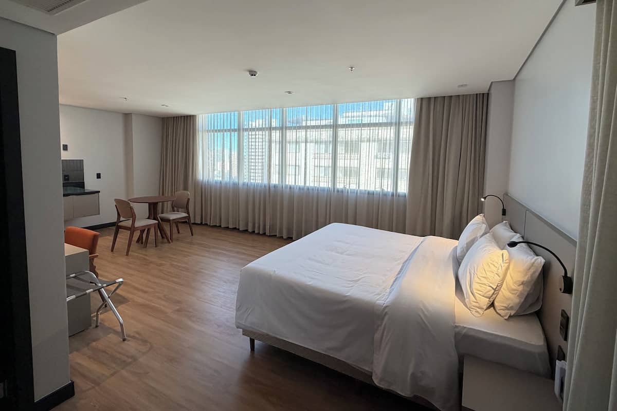 Quarto de hotel com uma cama, uma escrivaninha e uma cadeira.