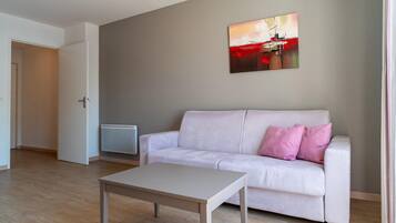 Uma sala de estar moderna com um sofá branco, uma mesinha, um radiador e um quadro na parede.