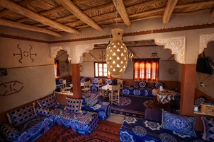 Um interior tradicional com vigas de madeira, almofadas estampadas e um lustre pendurado.