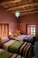 Quarto com duas camas, um candeeiro pendente e janela com cortinas.