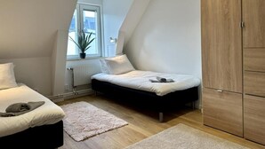 Quarto com cama, guarda-roupa, radiador, janela e uma planta.