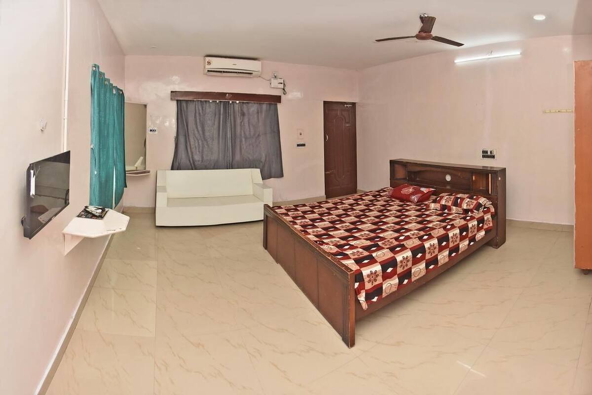 Quarto com cama, televisão, ventilador de teto e ar condicionado.