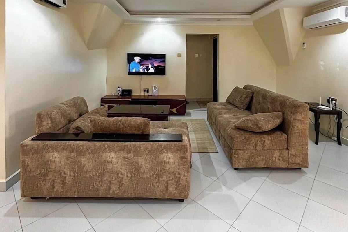 Uma sala de estar com dois sofás, uma televisão e unidades de ar condicionado instaladas no teto.