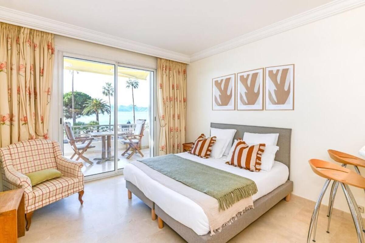 Quarto com cama, cadeira, mesa e vista para o exterior.
