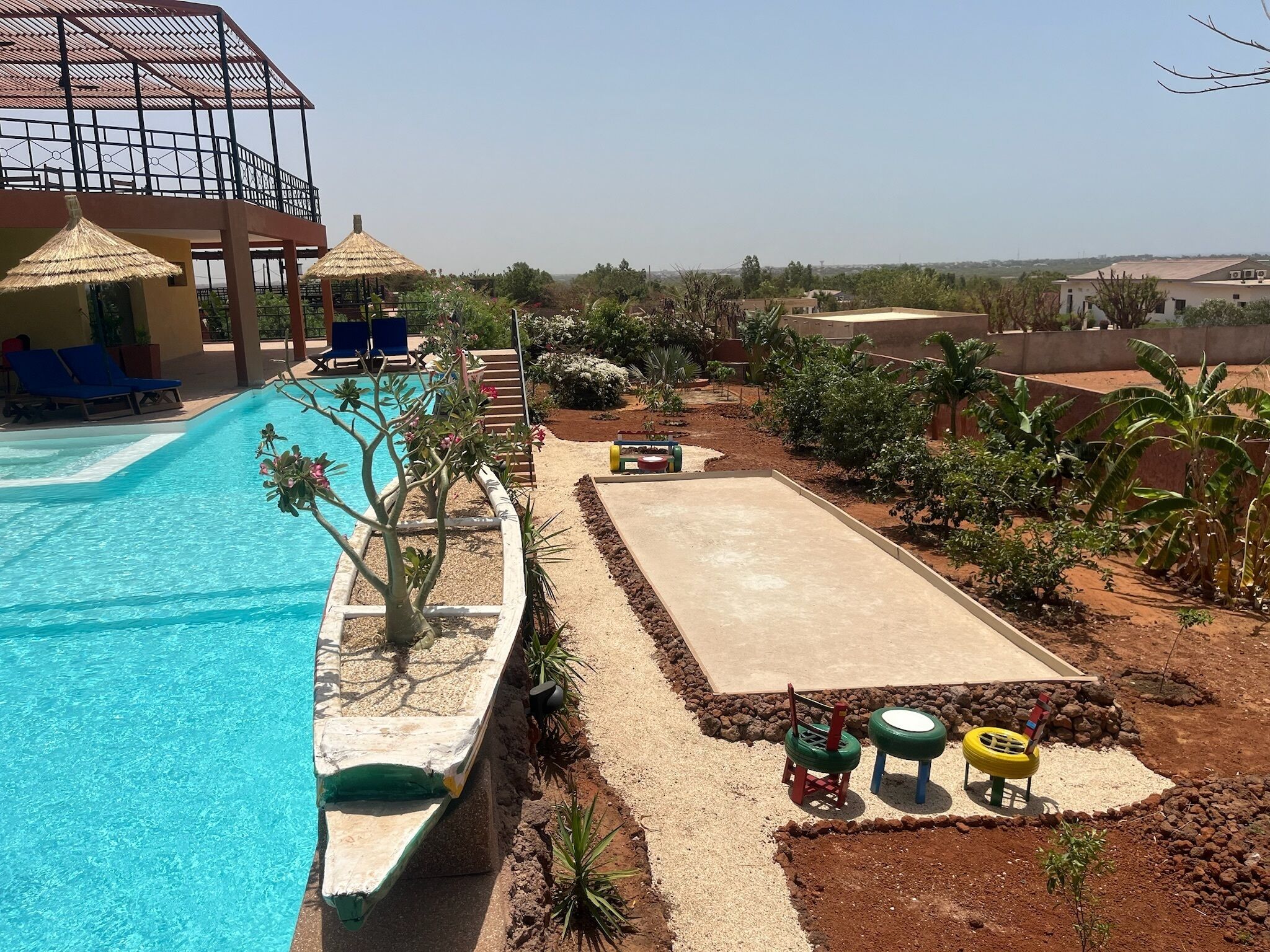 Piscina com espreguiçadeiras, área de estar coberta e vista para a paisagem ao redor.