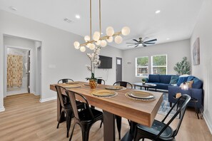 Uma sala de jantar moderna com mesa de madeira, cadeiras pretas e um lustre.