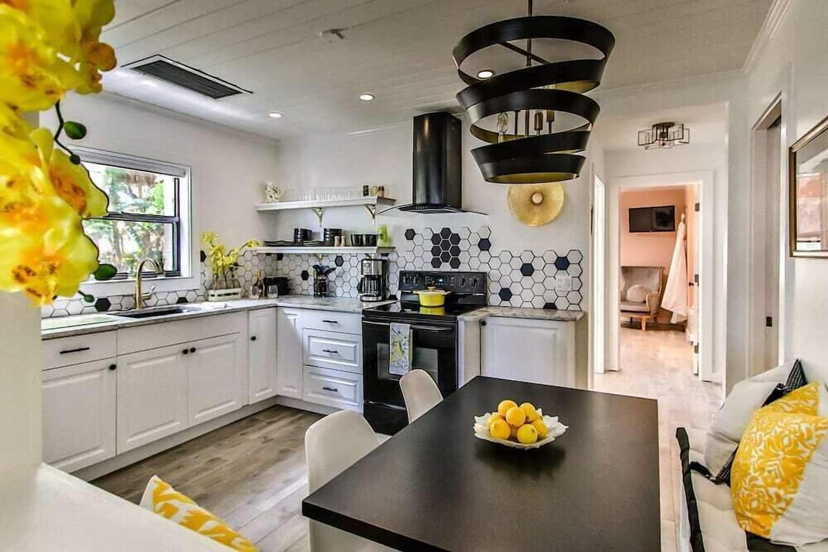Uma cozinha moderna com armários brancos, bancada preta e um revestimento hexagonal diferenciado.