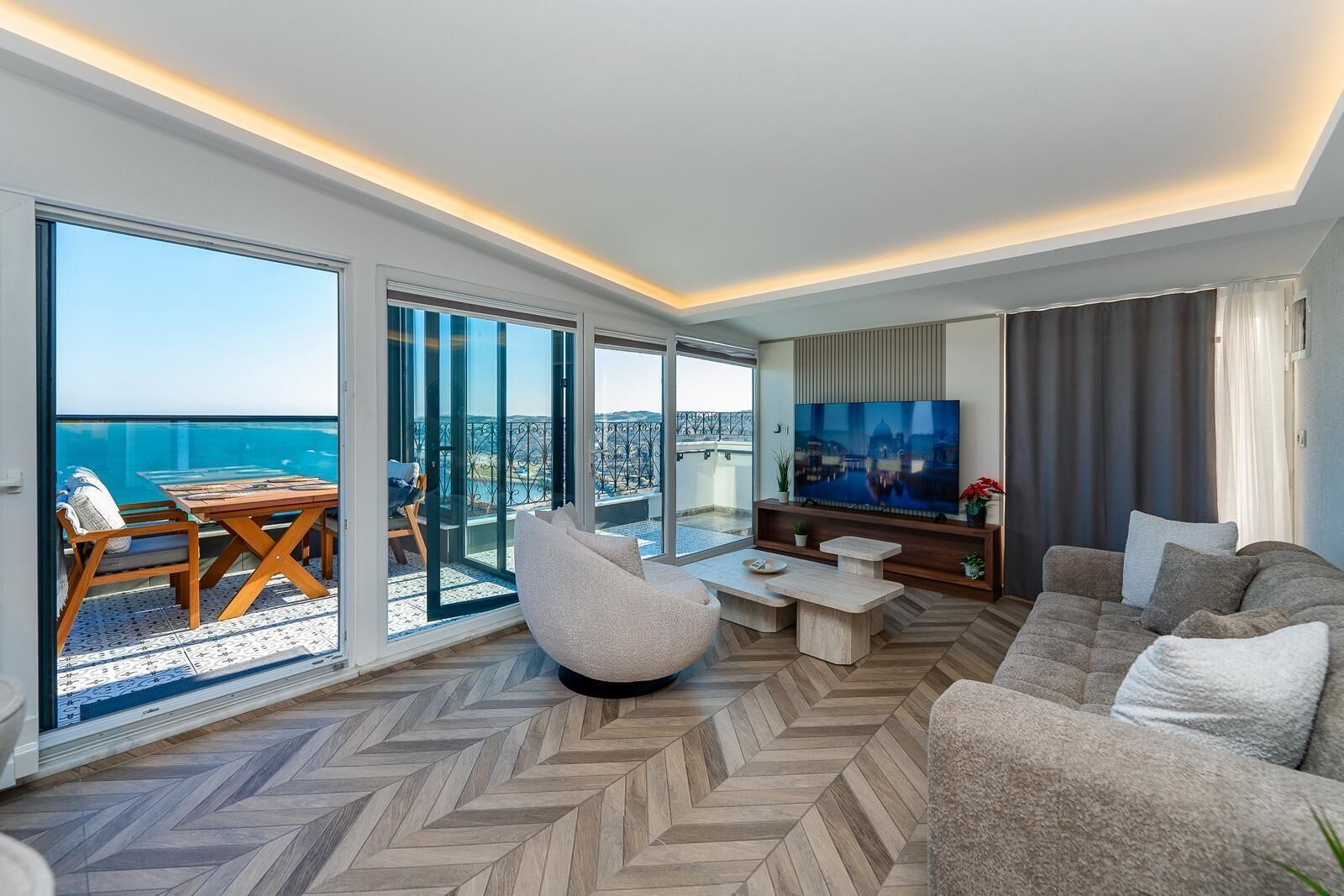 Uma sala de estar moderna com uma televisão grande, assentos confortáveis e uma varanda com vista.