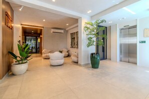 Um lobby moderno com balcão de recepção, área de estar e elevador.