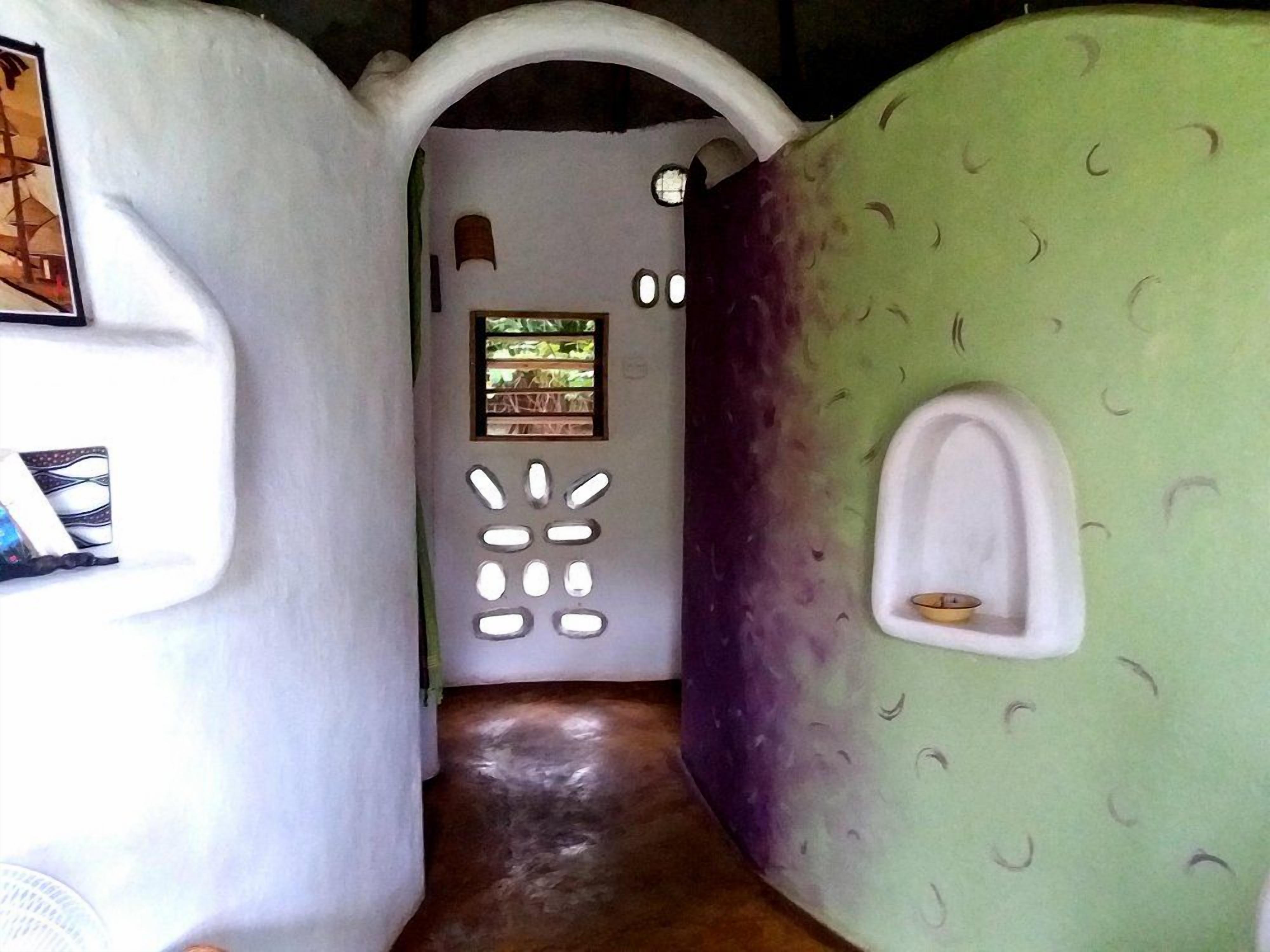 Quarto com design exclusivo, apresentando uma parede verde com padrão de pequenos círculos e uma porta branca com janela.