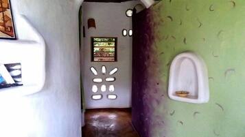Quarto com design exclusivo, apresentando uma parede verde com padrão de pequenos círculos e uma porta branca com janela.