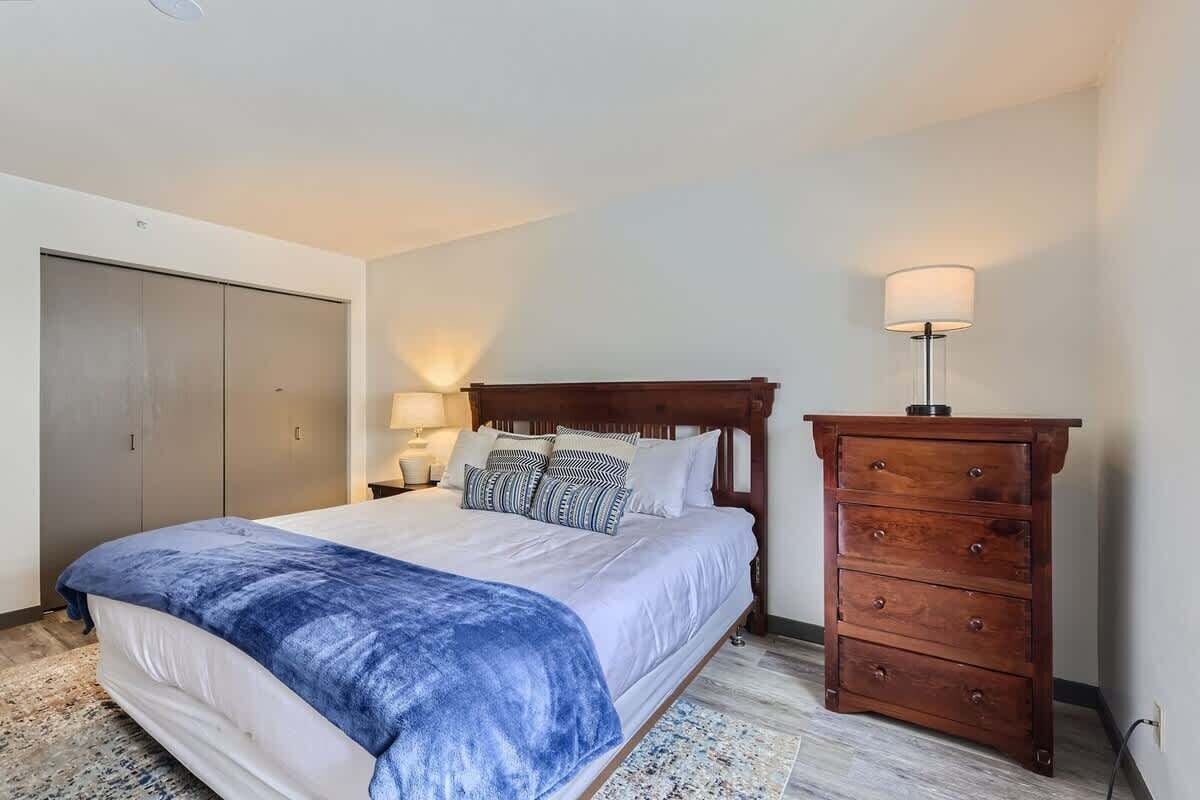 Quarto com cama, penteadeira, mesa de cabeceira e abajur.