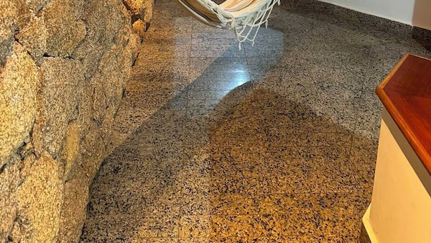 Quarto com uma rede em frente a uma parede de pedra, uma porta com uma placa e piso de madeira.