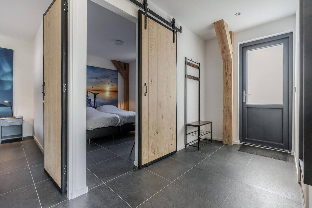 Quarto moderno com porta deslizante, uma cama, uma mesinha e uma escada.