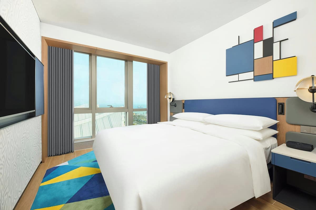 Quarto de hotel com uma cama grande, televisão, escrivaninha e janela com vista.