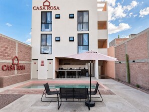 Edifício com a placa 'CASA ROSA', piscina, área de estar externa e cozinha aparente.