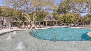 Piscina límpida com espreguiçadeiras e um gazebo.