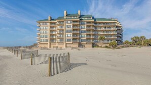 Um hotel com várias andares e varandas, situado numa praia de areia.