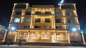 Um hotel de vários andares com uma entrada imponente, grandes janelas e fachada bem iluminada.