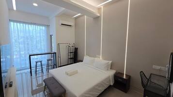Quarto de hotel moderno com uma cama grande, mesas de cabeceira, uma pequena escrivaninha e uma varanda com guarda-corpo.