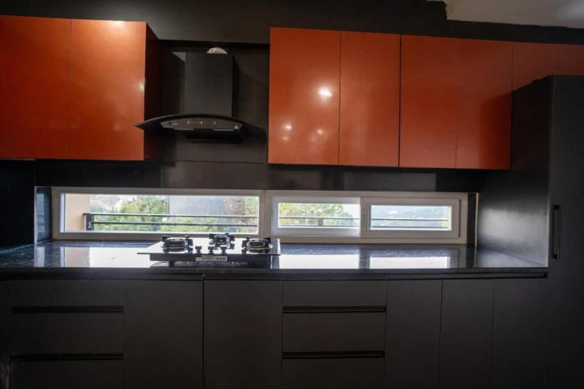 Cozinha moderna com janela, eletrodomésticos de aço inoxidável e armários escuros.