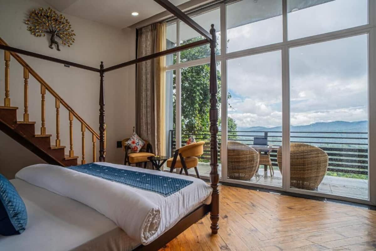 Quarto com cama de dossel, escada, vista para o exterior e mobiliário de vime.