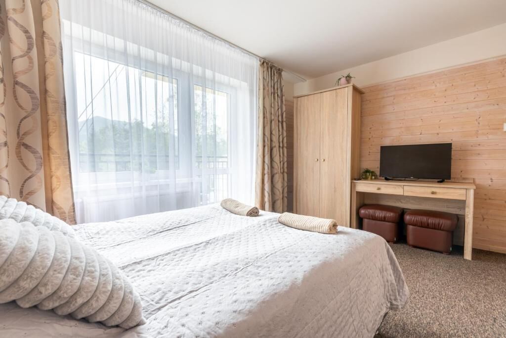 Quarto com uma cama, televisão sobre uma escrivaninha de madeira e um guarda-roupa.