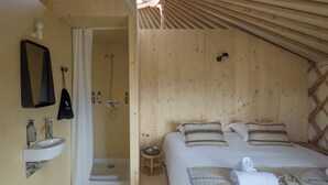 Quarto de madeira com uma cama, pia e chuveiro.