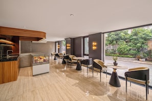 Interior moderno com cozinha, área de estar e grandes janelas com vista para o verde.