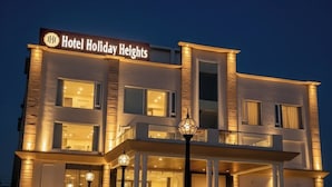 Um hotel de vários andares com uma placa grande que diz 'Hotel Holiday Heights'.