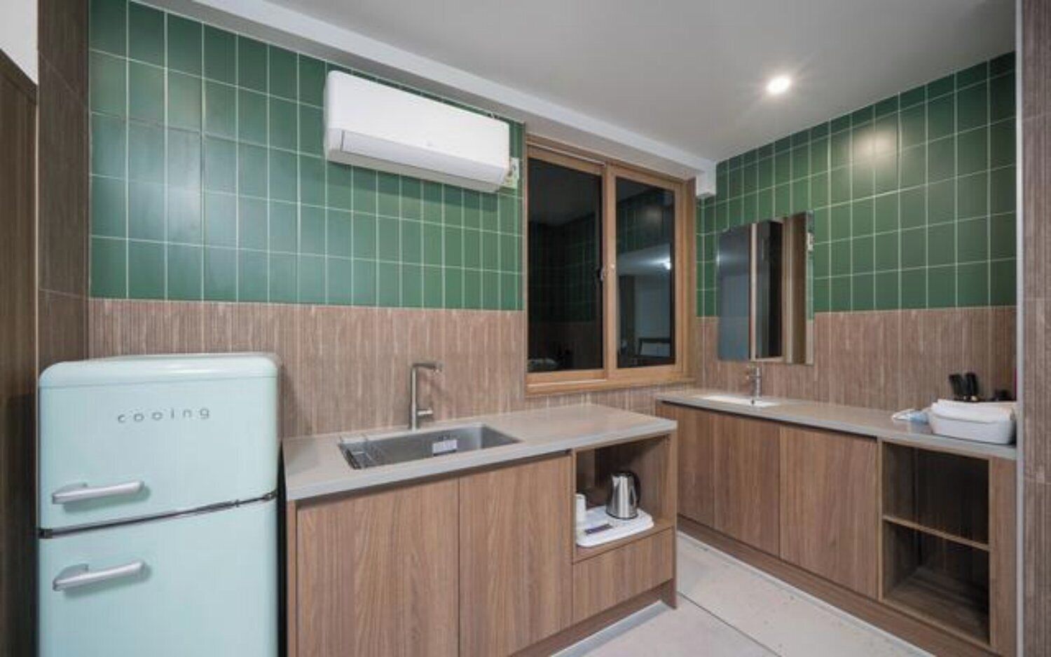Cozinha compacta com pia embutida, um pequeno refrigerador e armários de madeira.