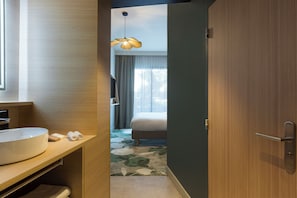 Quarto de hotel moderno com uma pia grande e redonda, uma cama, uma luminária no teto e um carpete com padrão floral.