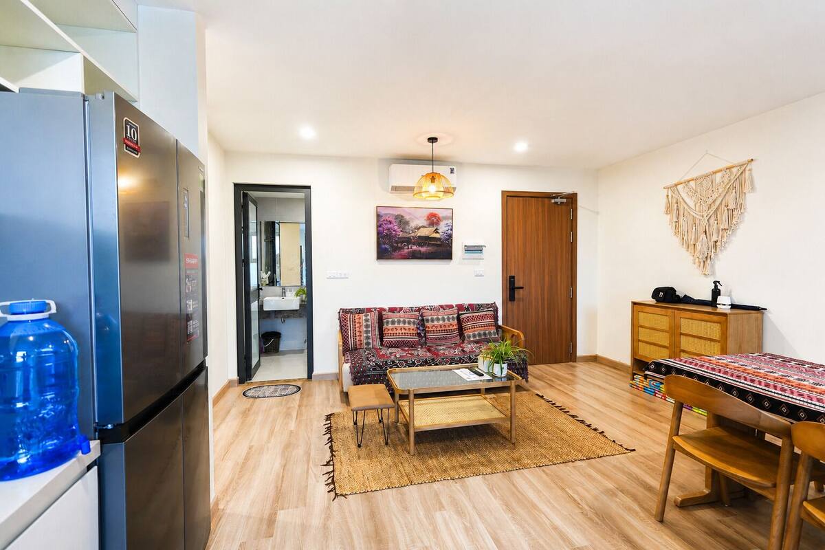 Um espaço compacto com cozinha compacta, sofá, mesa de jantar e um enfeite de macramé na parede.