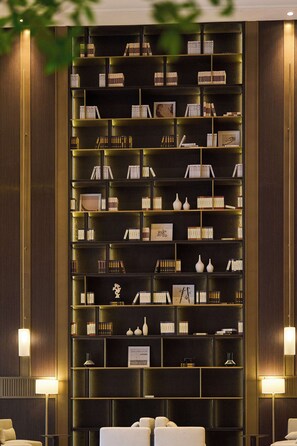 Uma grande estante de madeira escura cheia de livros e objetos decorativos, com duas luminárias de chão de cada lado.
