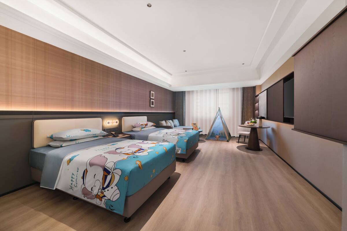 Quarto de hotel com duas camas, uma mesa pequena, uma tenda e uma TV.