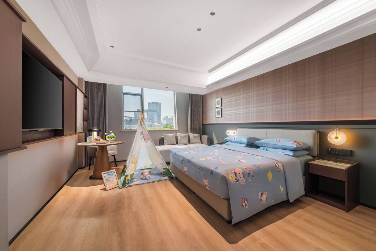 Quarto de hotel moderno com uma cama grande, uma escrivaninha, uma tenda e vista para a cidade.