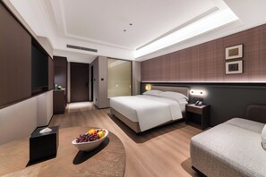 Quarto de hotel moderno com uma cama grande, mesa de cabeceira e uma cesta de frutas.