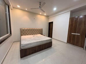 Quarto com cama, ventoinha no teto, guarda-roupa e janela.